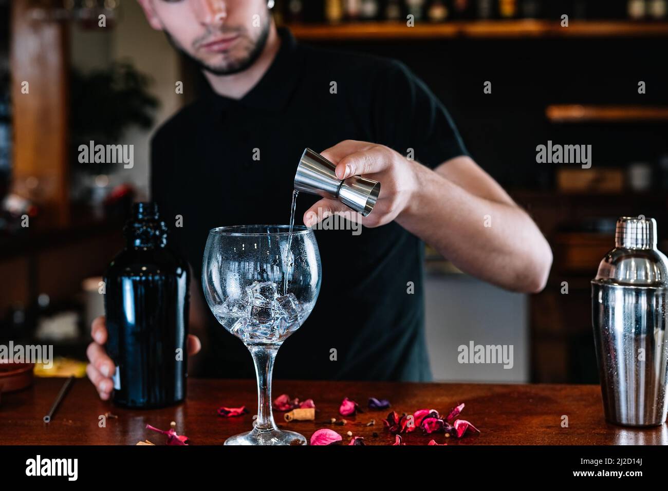 waiter pouring liquor into a glass cup to prepare a mixed drink on the ...