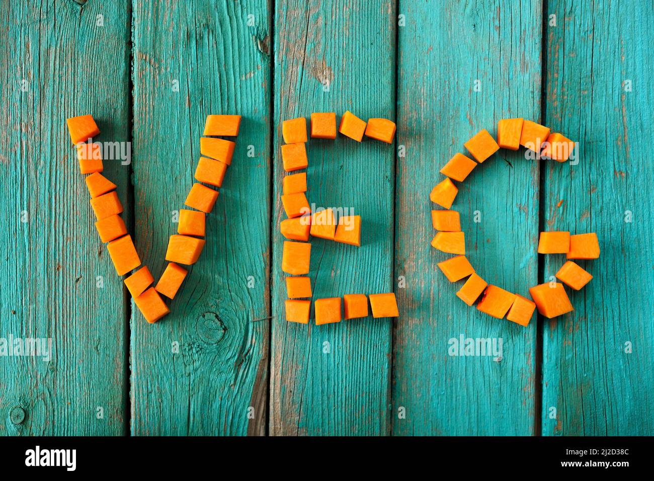 Word Veg written with raw pumpkin pieces on wooden turquoise table top ...