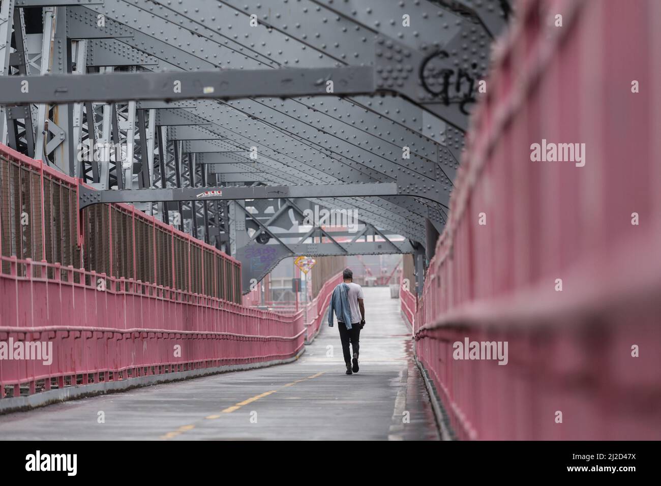Solo casual man walking the cycling lane on Williamsburg Bridge ...