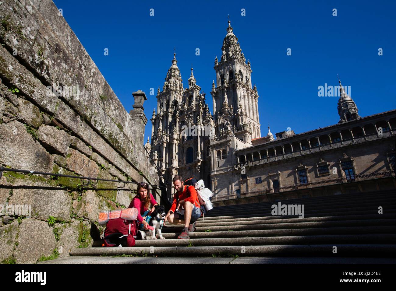 Two pilgrims finish the Camino de Santiago and rest on the steps of ...