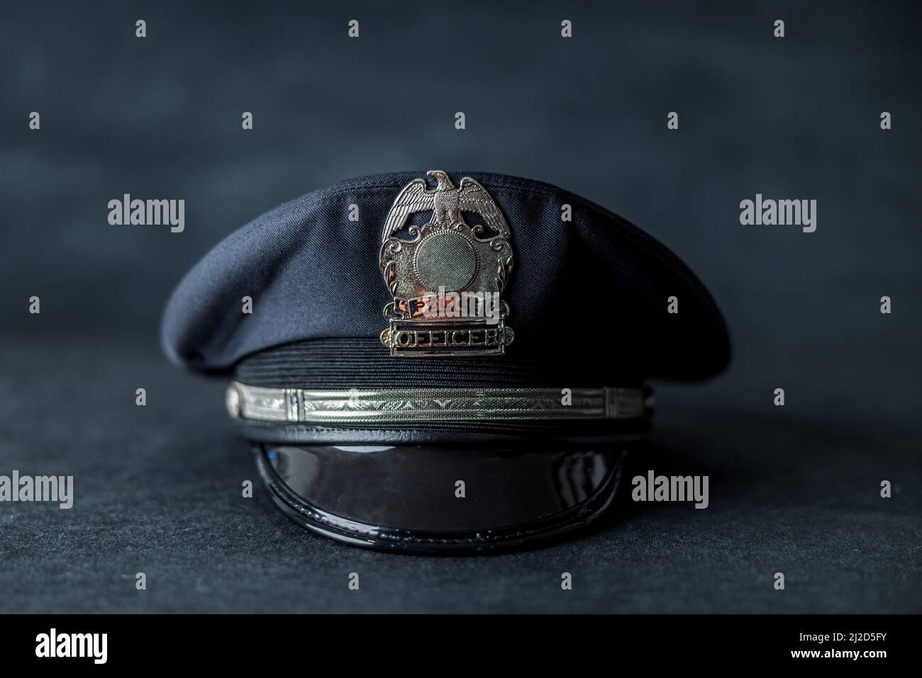 A navy blue police hat cap in front of a navy blue background with ...