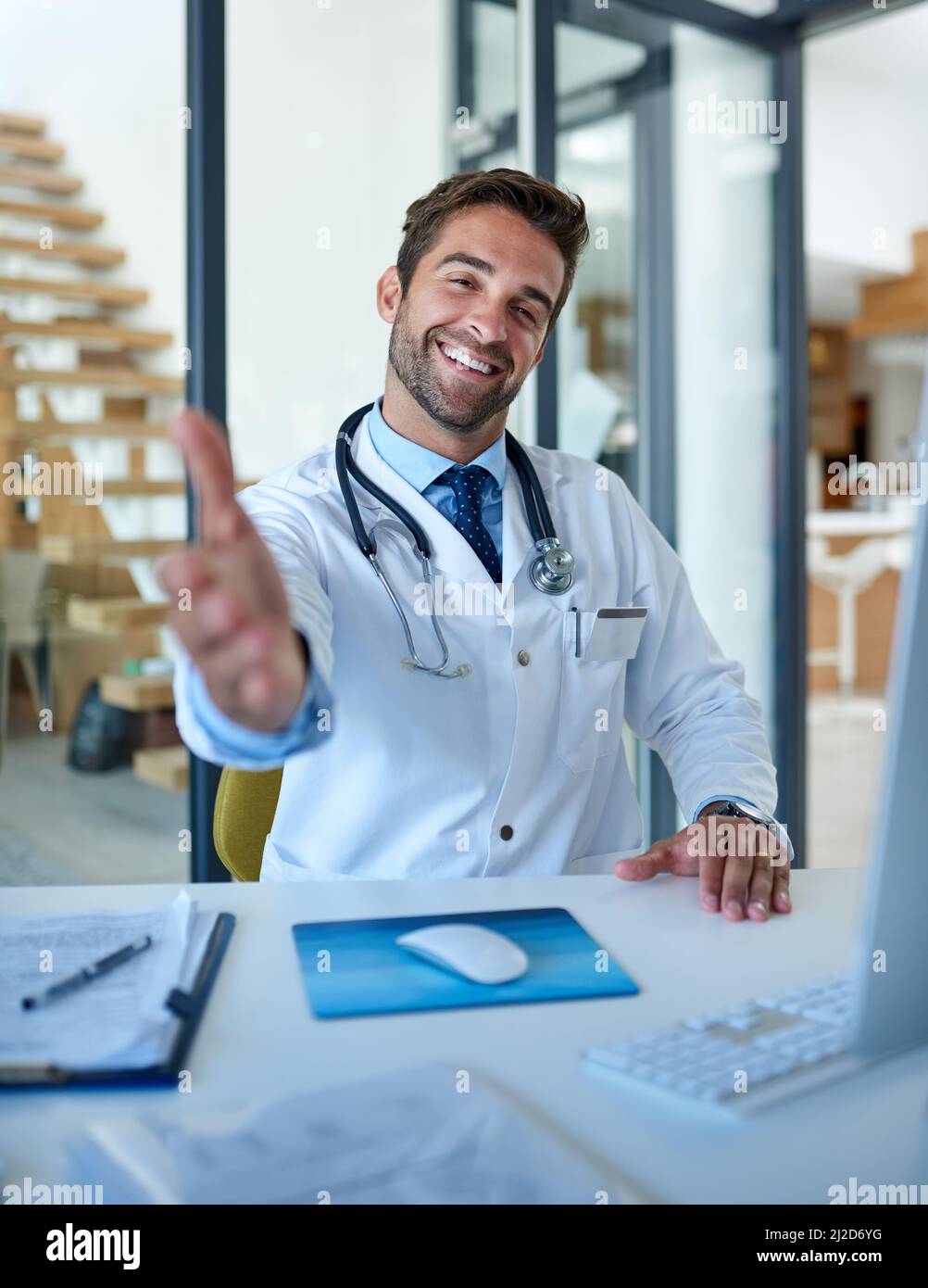 Have a seat and lets discuss your health. Portrait of a young doctor ...