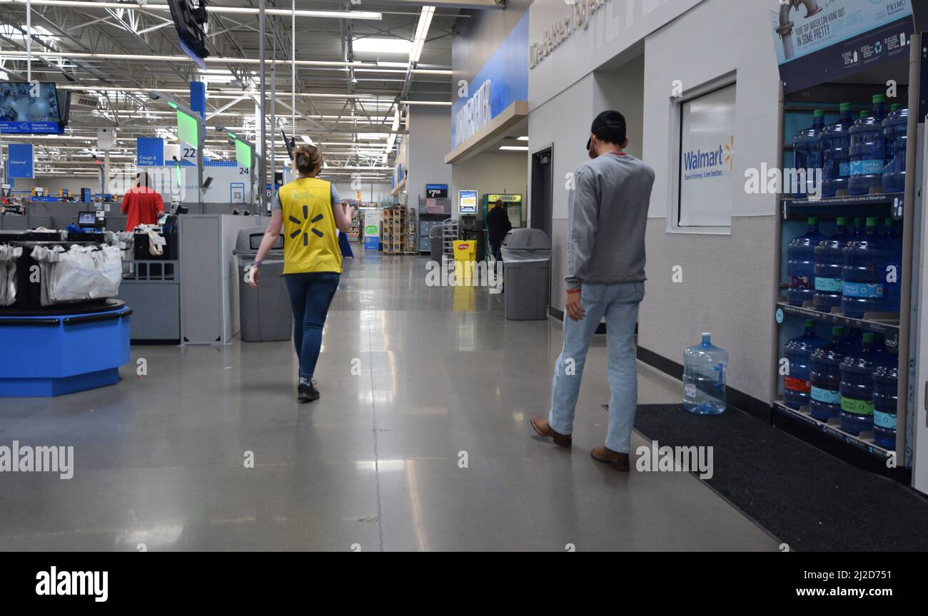 A Gen Z man walking behind a worker inside a Cheyenne Wyoming Walmart ...