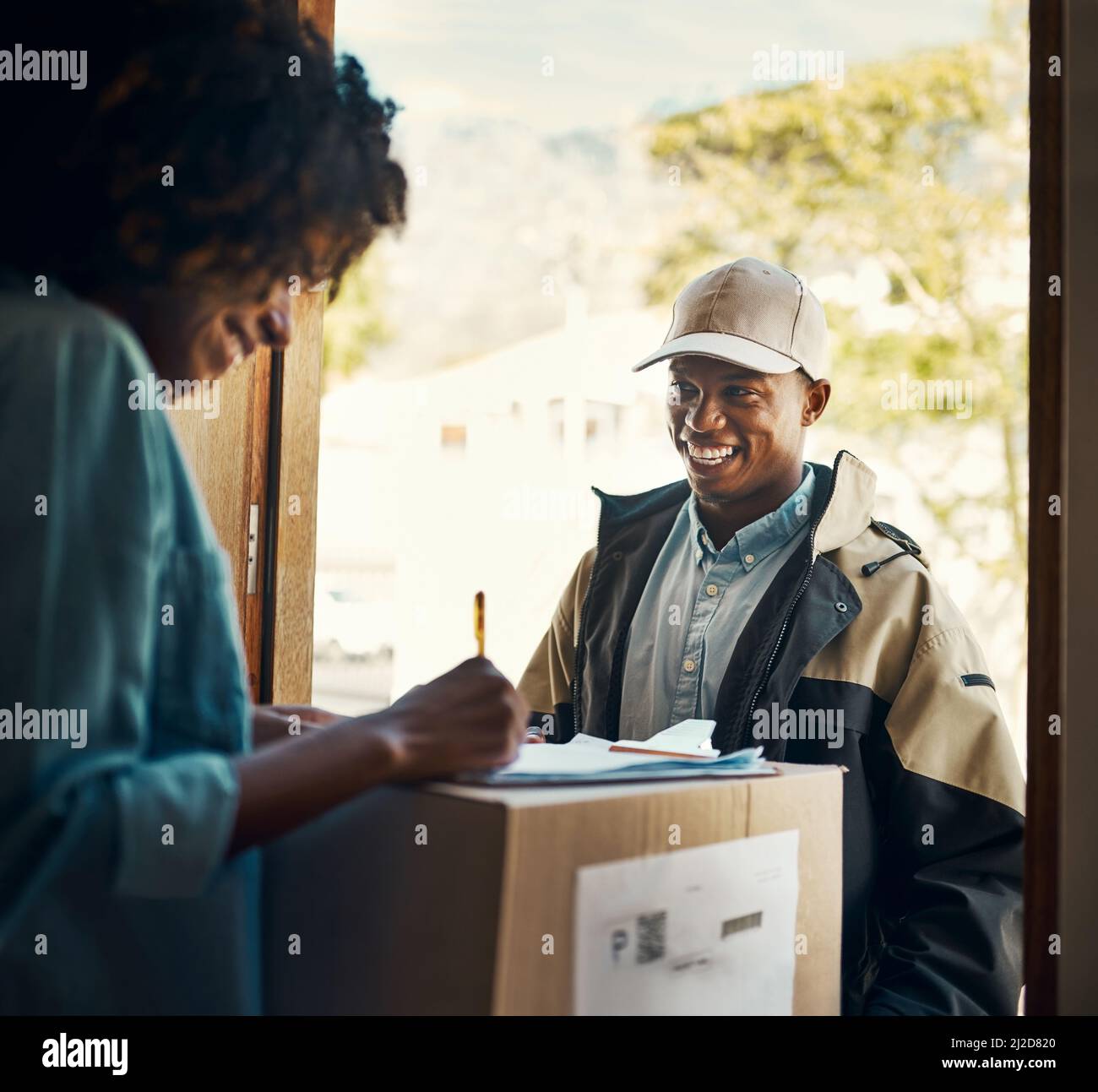 Signed and delivered. Shot of a cheerful young woman signing a form ...