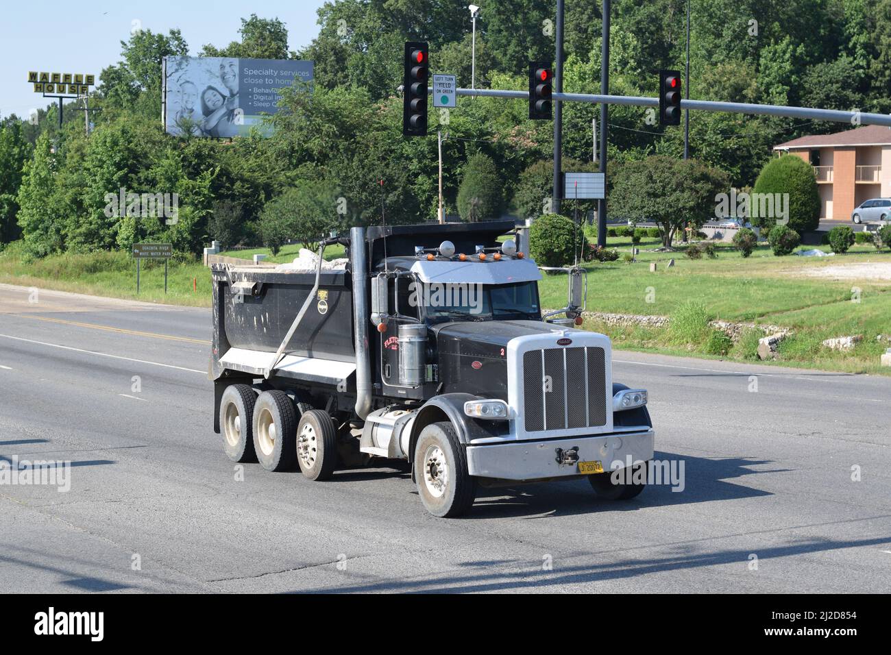 Black dump truck filled with broken slabs of concrete driving on a four ...