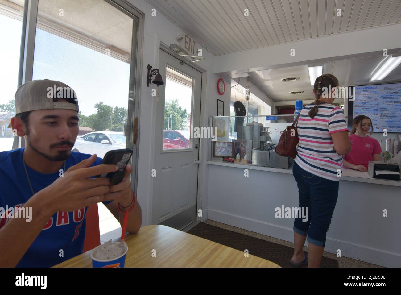A young man at the edge of Gen Z texts inside a Dairy Queen restaurant ...