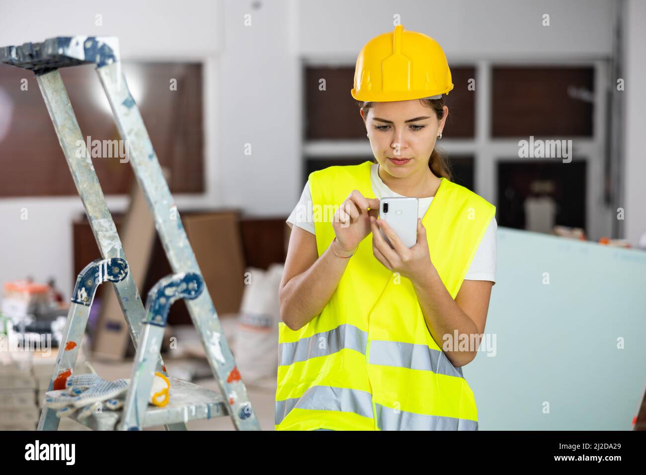 Focused female foreman using smartphone at construction site Stock ...