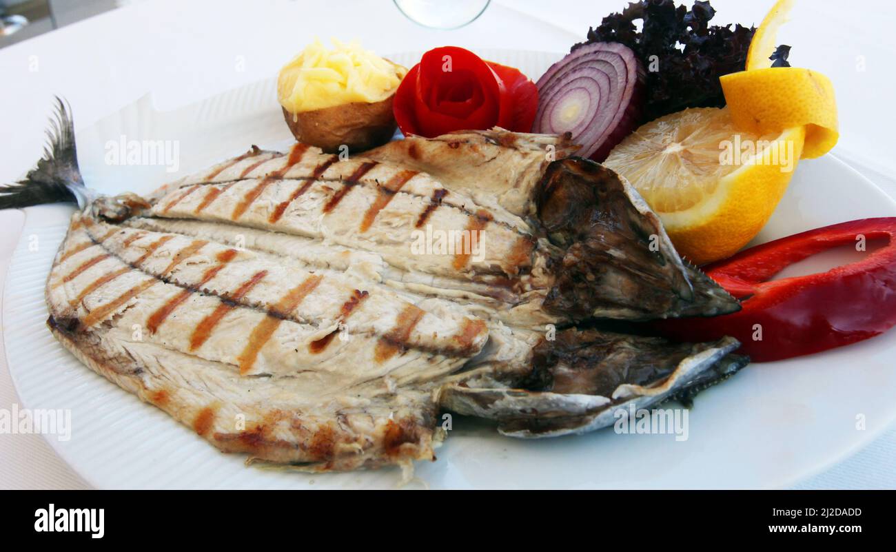 Grilled perch fish (Turkish: Levrek) with potato, lemon and tomato on ...