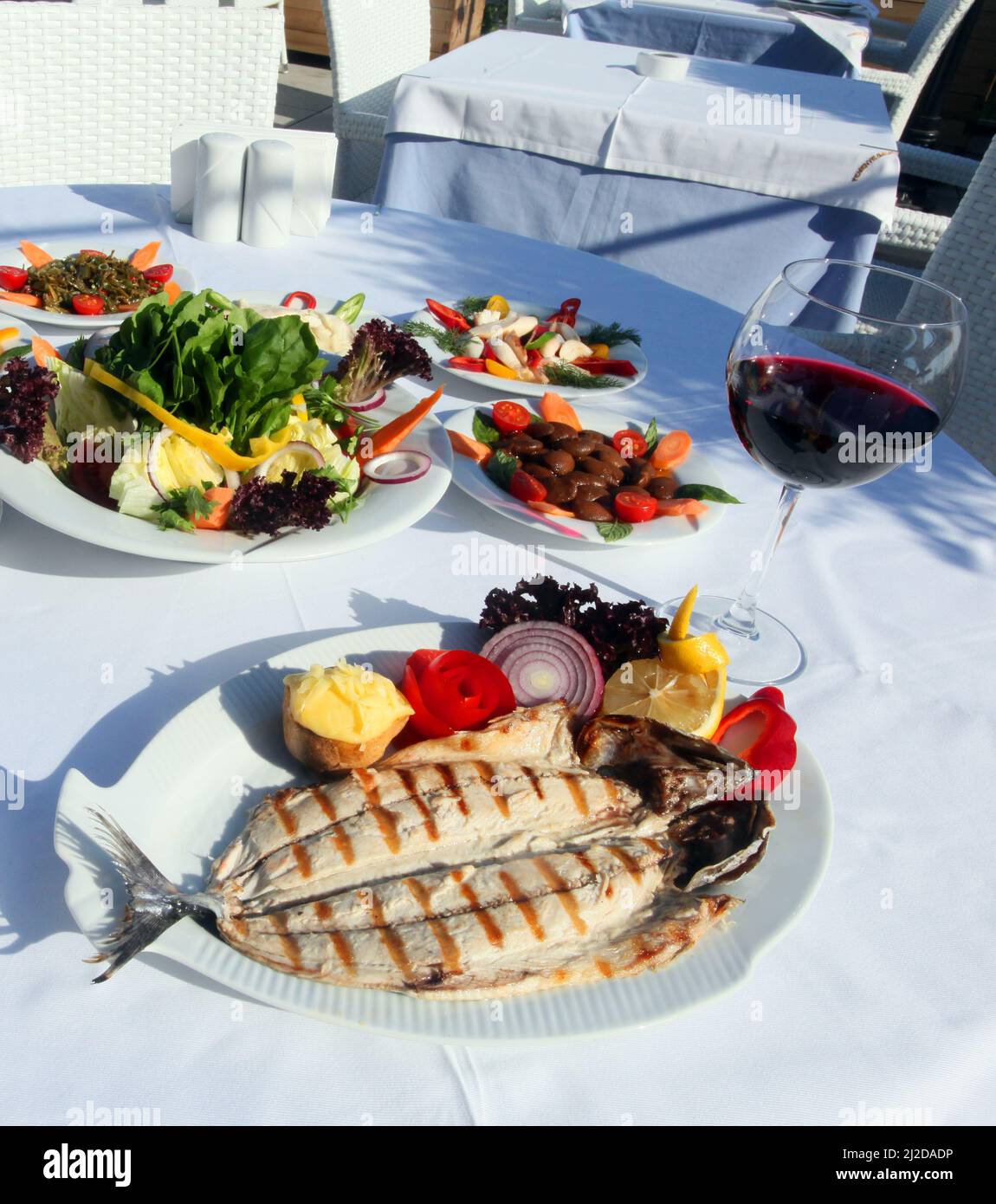 Grilled perch fish (Turkish: Levrek) with appetizer foods and red wine ...