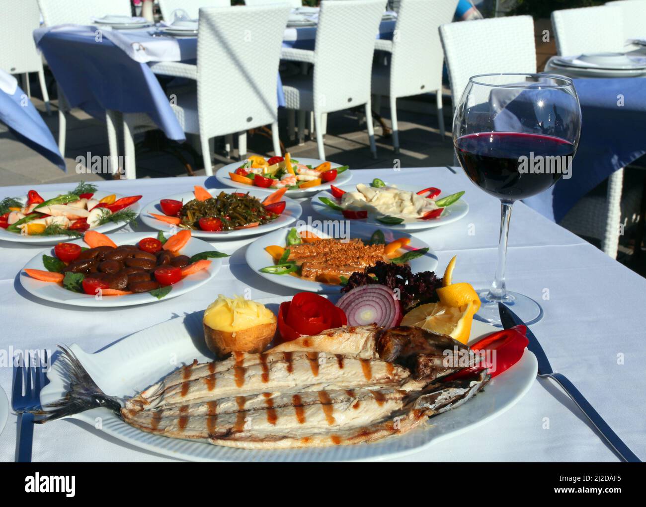 Grilled perch fish (Turkish: Levrek) with appetizer foods and red wine ...