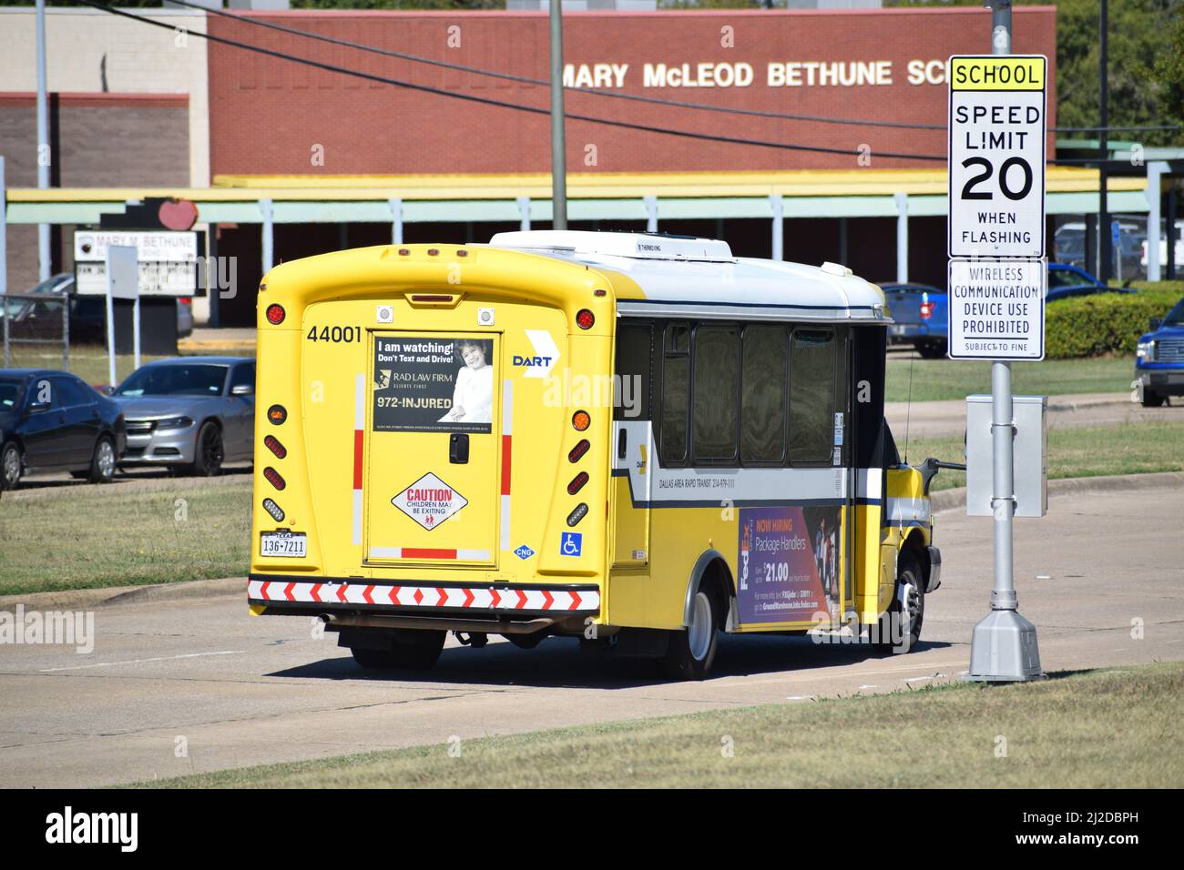 Small yellow Dallas Area Rapid Transit bus driving through a school ...