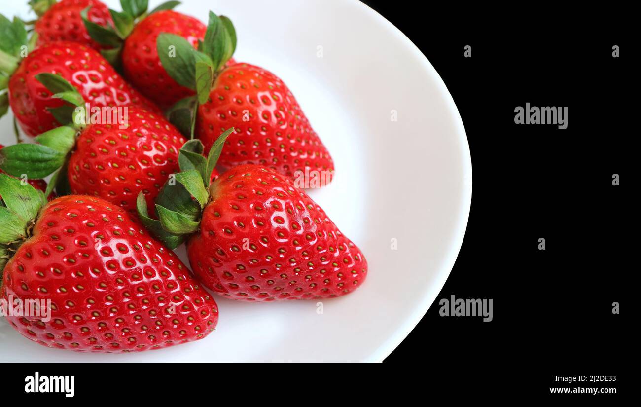 Plate of vibrant red fresh ripe strawberries on back backdrop Stock ...