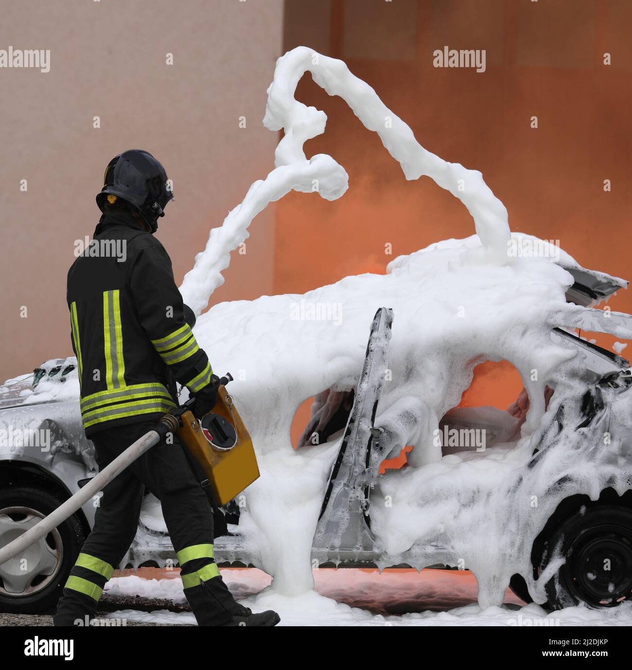 firefighter throws the foam to put out the fire of the crashed car ...