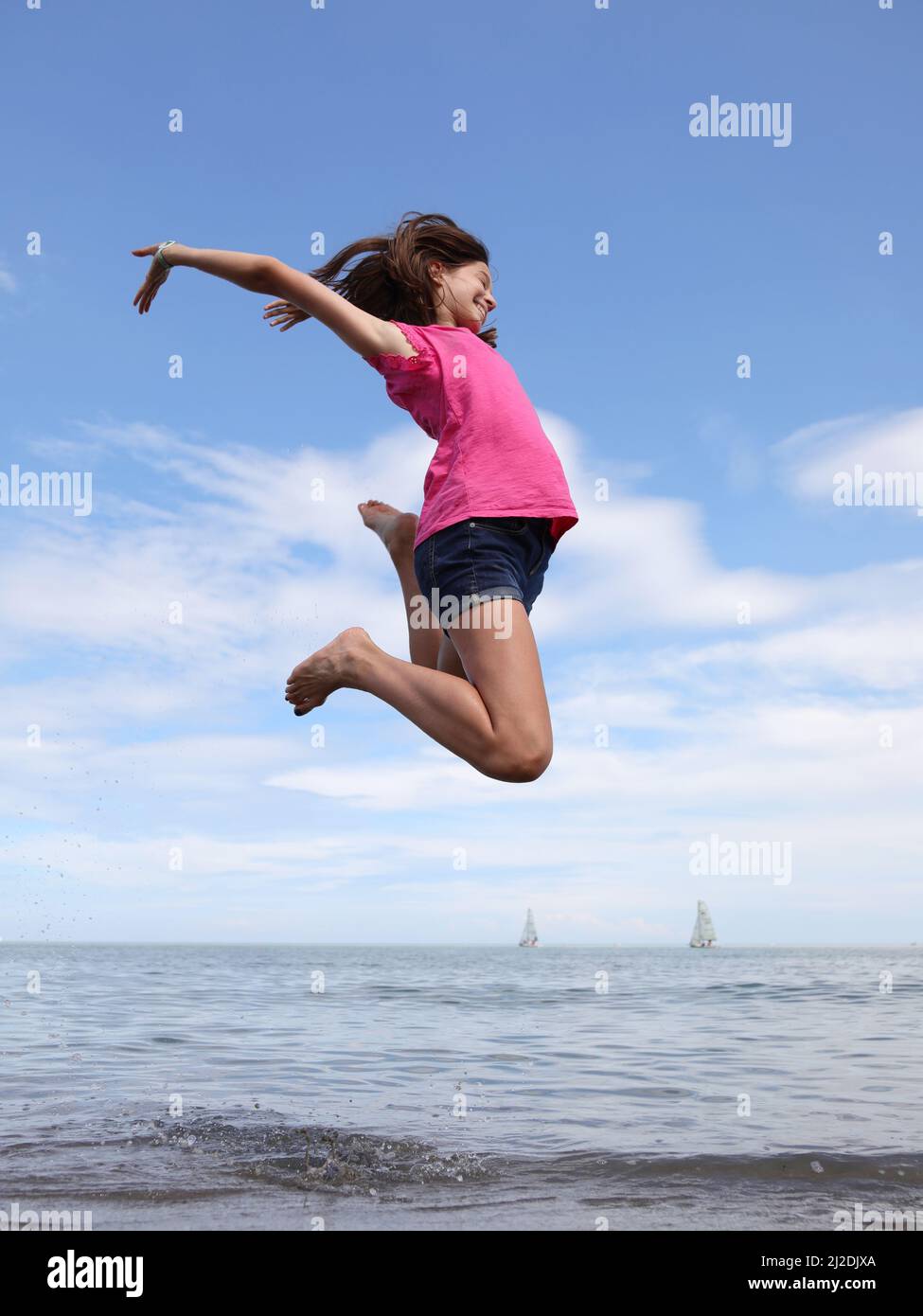 young girl make a very high jump on the seashore a symbol of joy and ...