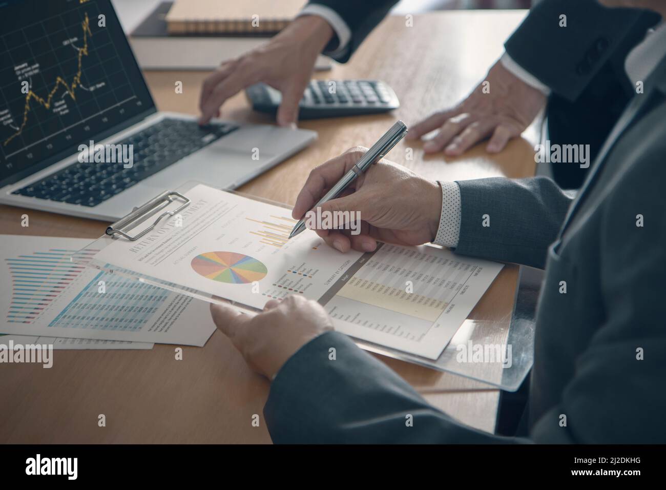 Two businessmen with laptop computer review financial statements for ...