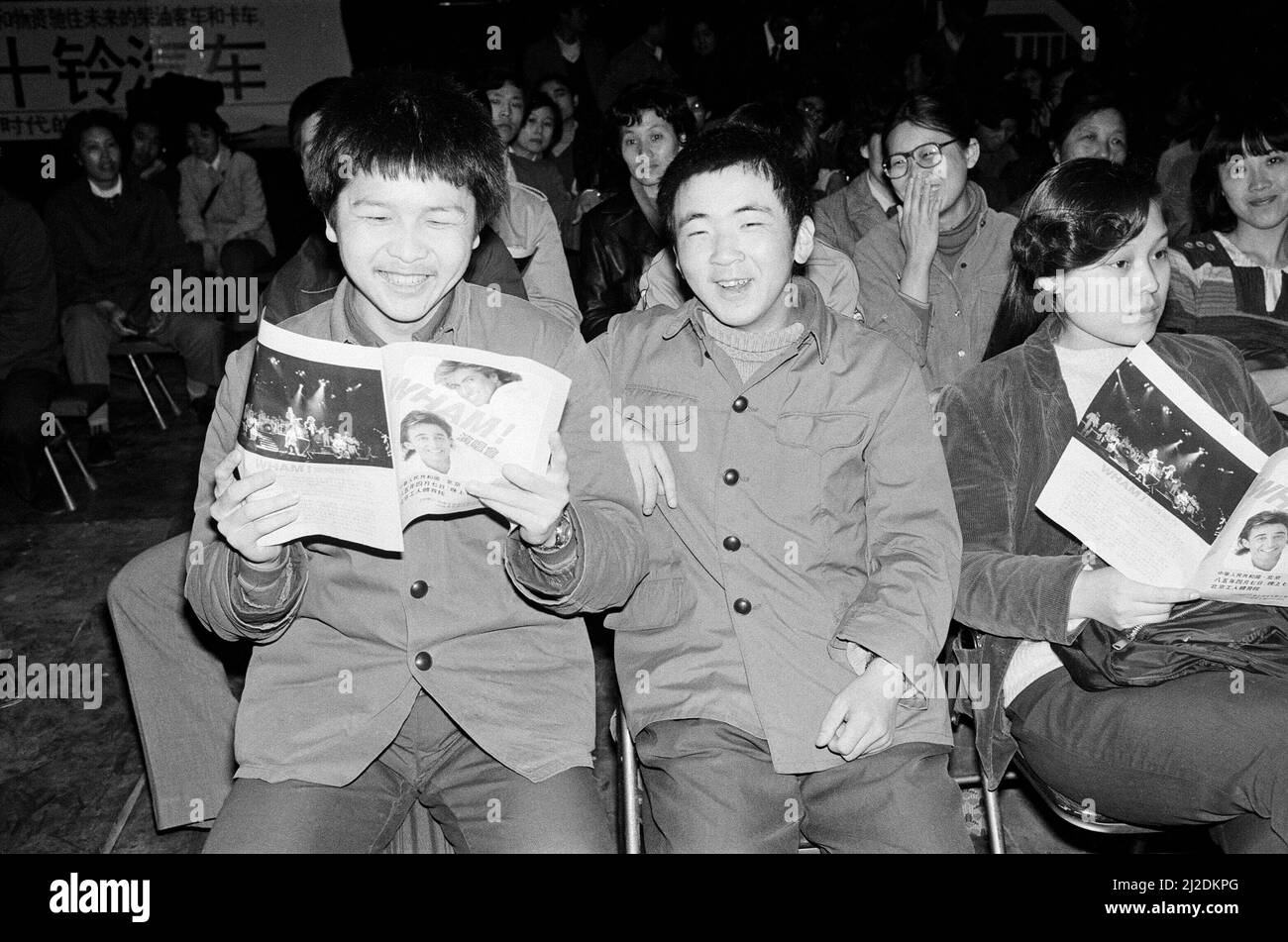 Fans, holding their programme, enjoy the performance of George Michael ...