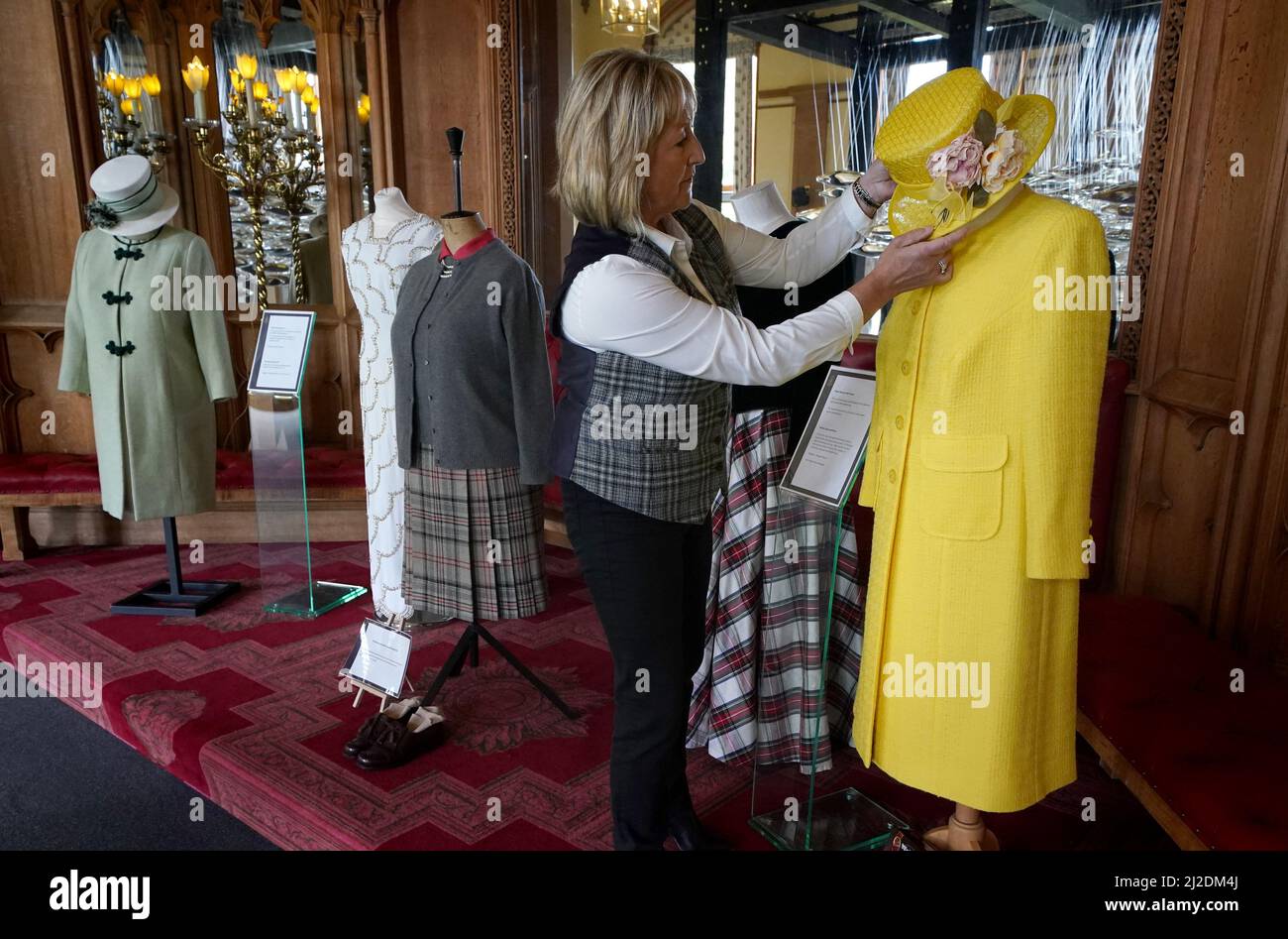 Assistant curator Sarah Hoare adjusts outfits worn by Queen Elizabeth ...