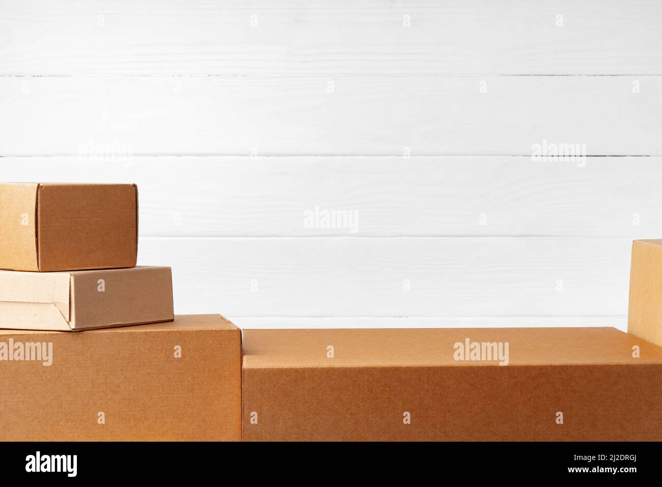 Group of cardboard boxes against white wooden wall Stock Photo - Alamy