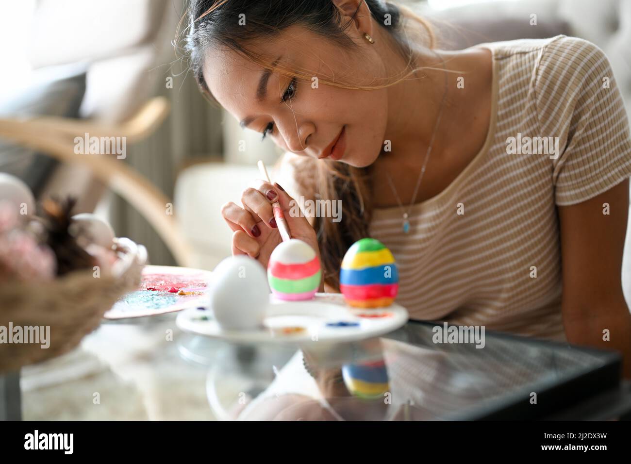 Relaxed and clam woman painting on an Easter egg with a colourful ...