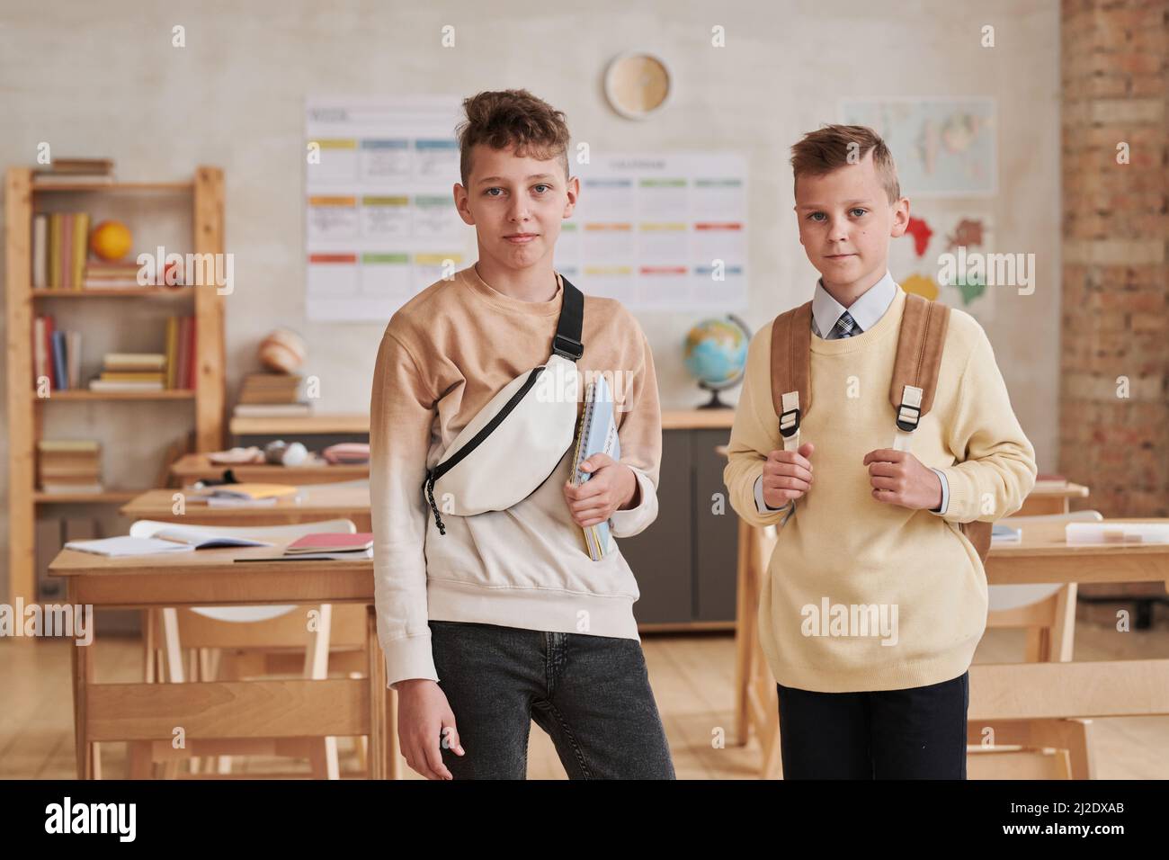 Waist up portrait of two teenage boys in school looking at camera while ...