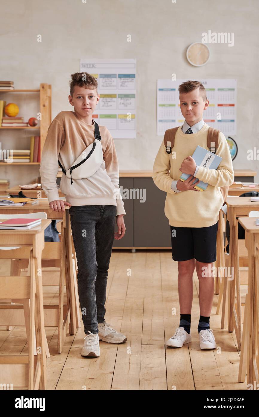 Vertical full length portrait of two teenage boys in school looking at ...
