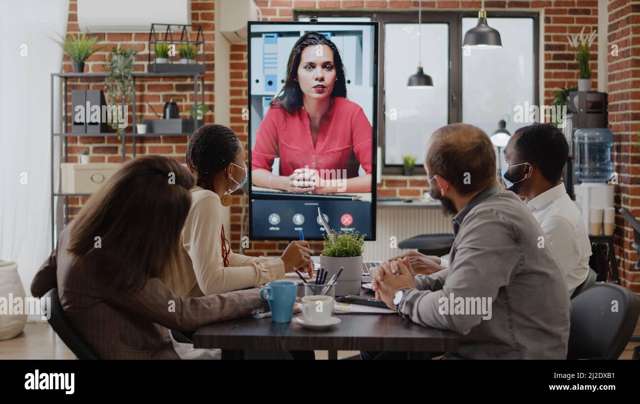 Colleagues meeting with woman on video call conference, using remote ...