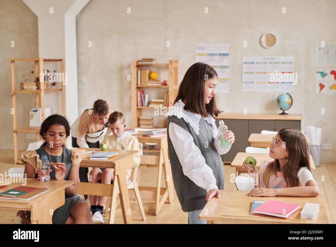 Diverse group of children chatting in school classroom during break ...