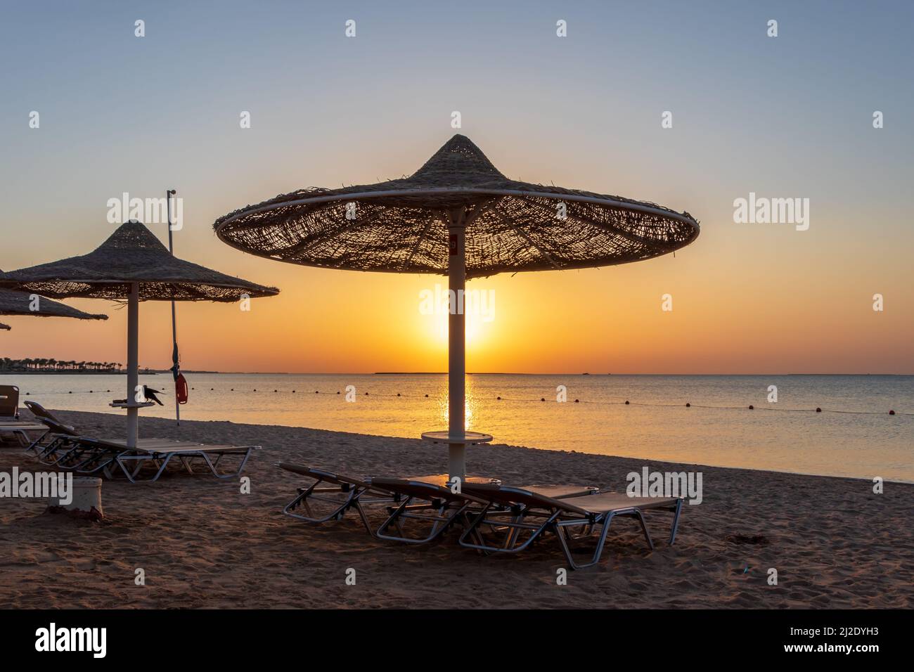 Sunrise on the beach with parasol overlooking the Red Sea in Hurghada ...