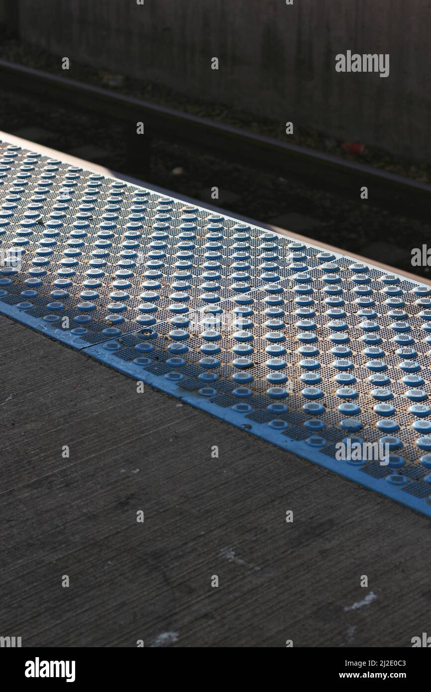 The bright blue textured safety alert surface on the edge of the public ...