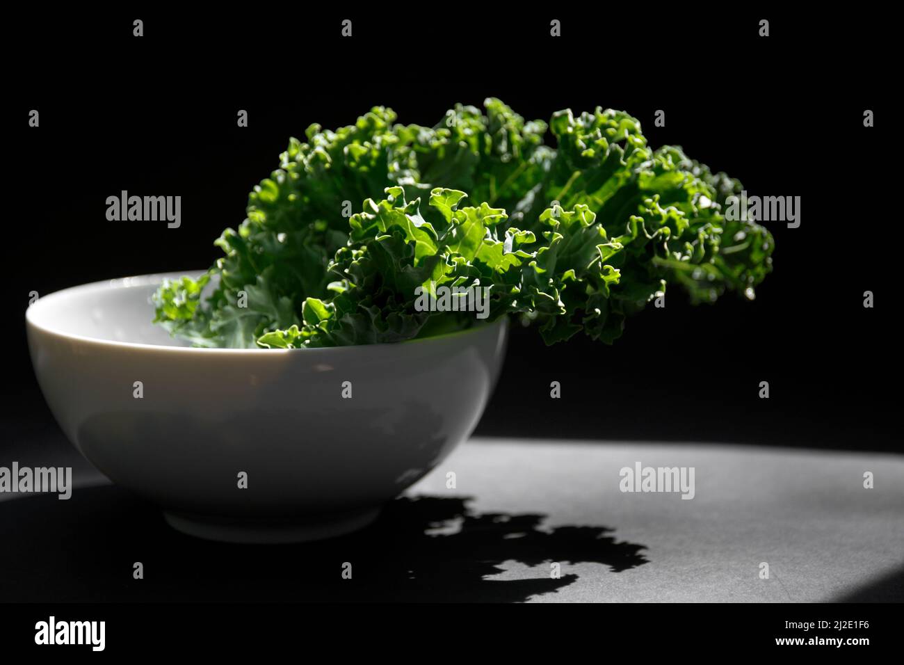 Kale, leaf cabbage. Curly green cabbage leaf in a white bowl on a dark ...