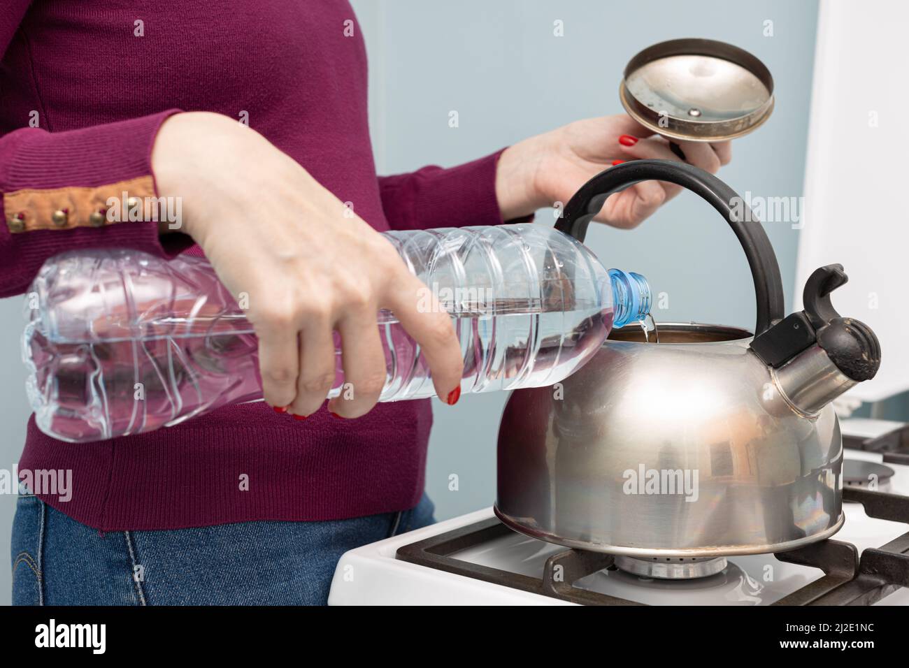 woman pouring clean water from a bottle into a kettle. High quality ...