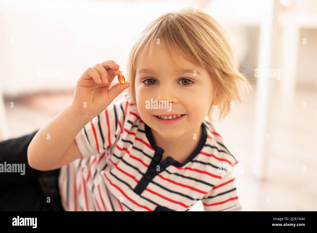 Cute little child, toddler boy, eating alfa omega 3 child suplement ...