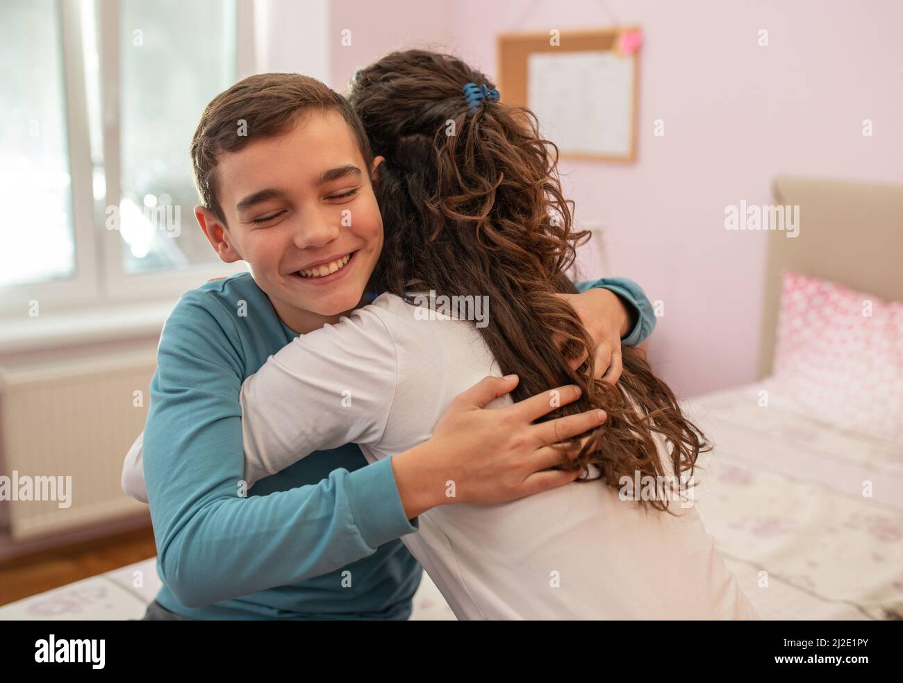 Mother and sun hugging on a bed in bedroom while son smiling and ...