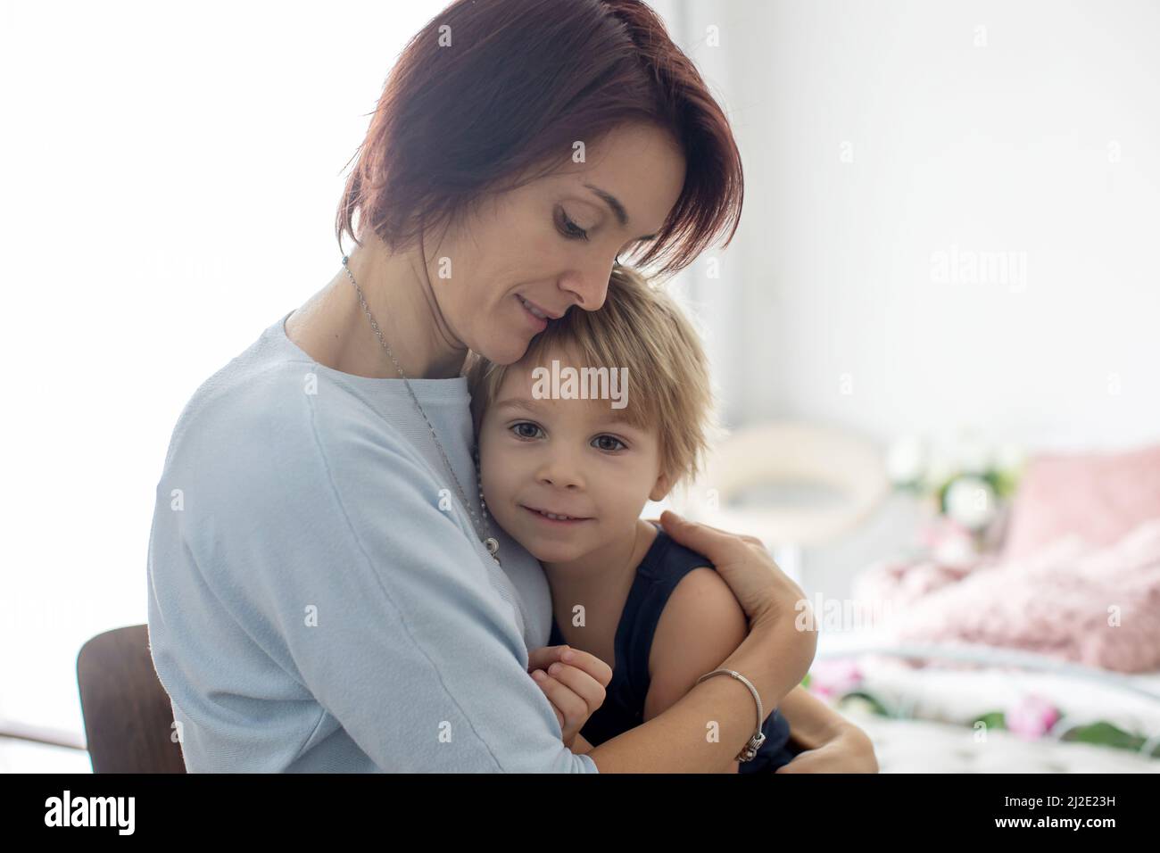 Portrait of mother and child, hugging on a back lit white background ...