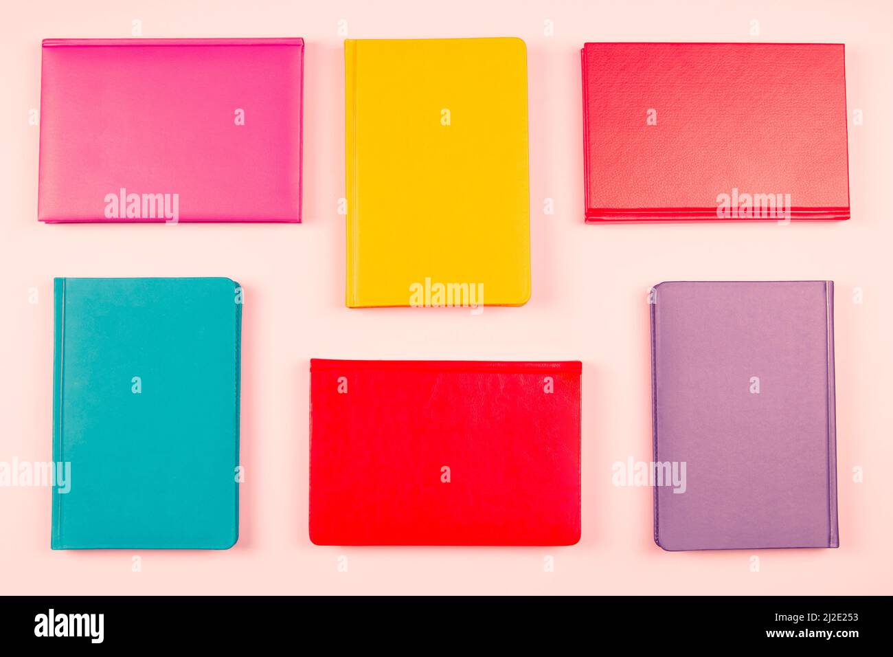 Colorful hardcover books arranged on pastel pink background. Top view ...