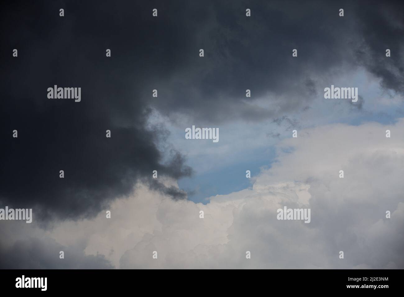 A white cloud collides with a dark thundercloud against a background of ...