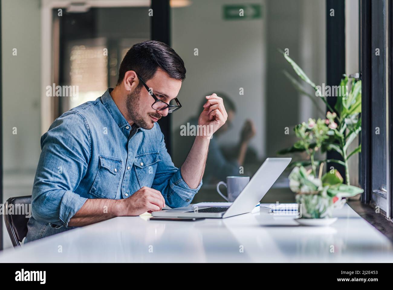 Focused adult man, finishing his assignments on time, at the office ...