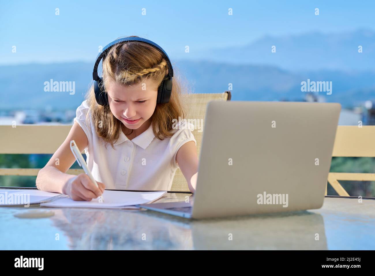 Girl child with headphones is studying using a laptop Stock Photo - Alamy