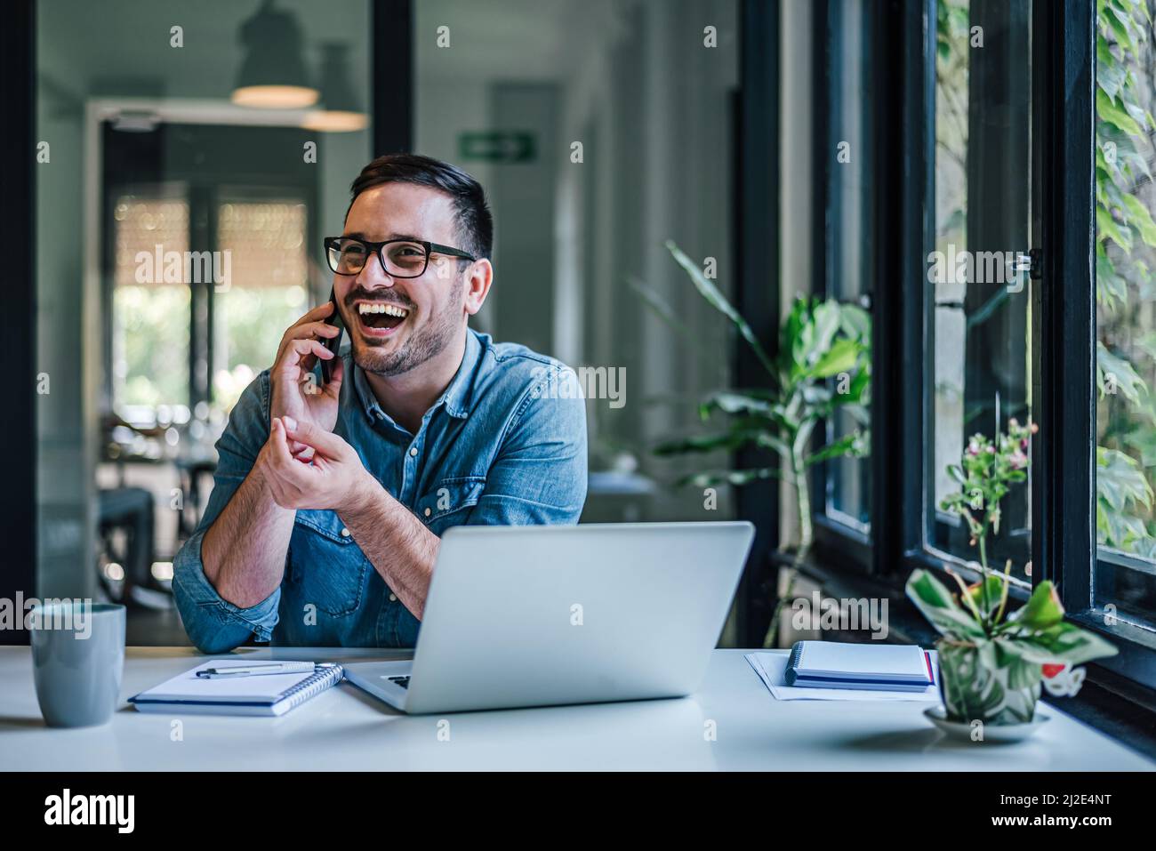 Happy adult man, having fun at work, while talking on his phone in the ...