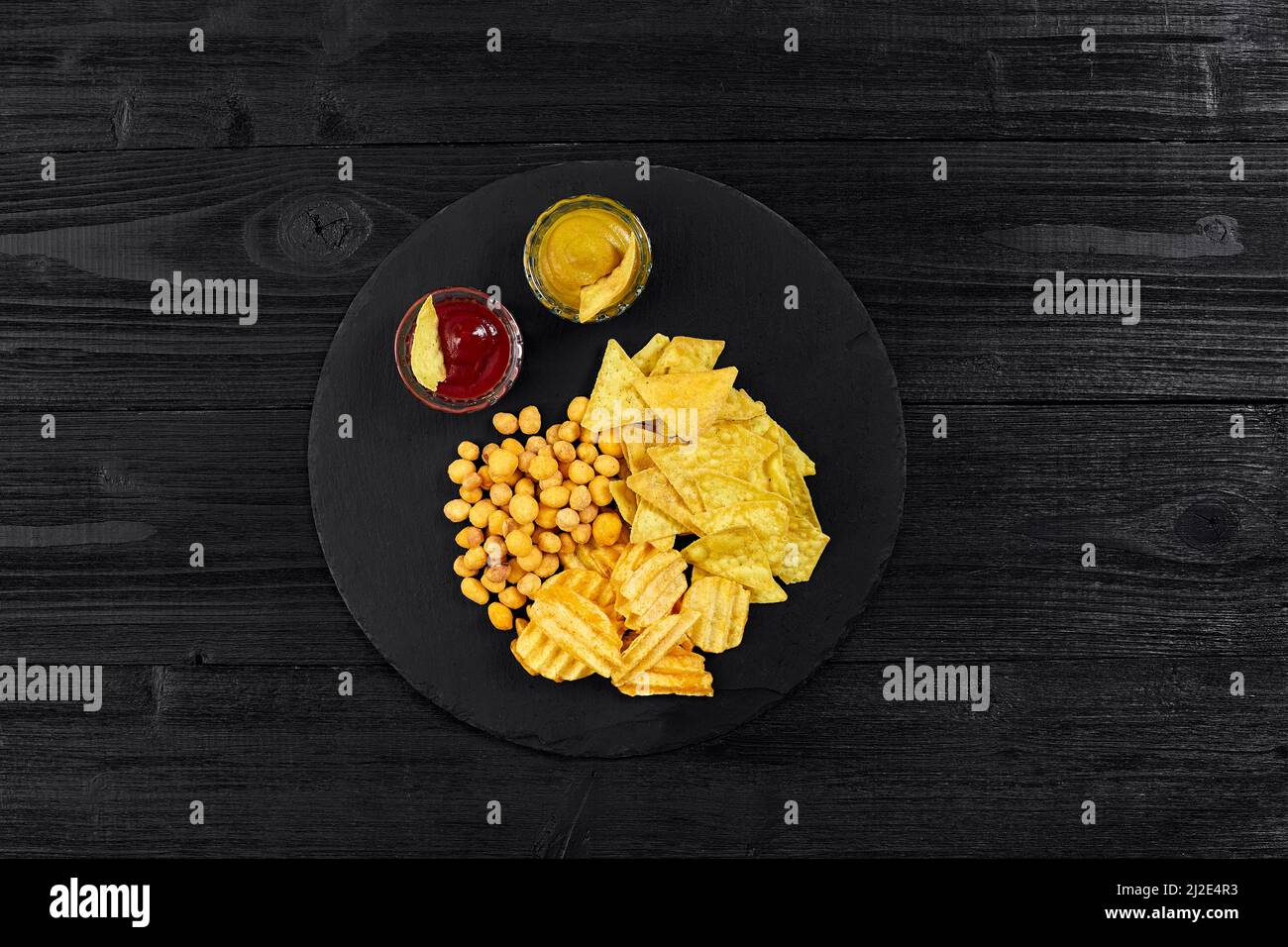 Overhead view of snacks with sauce on black wooden table Stock Photo ...