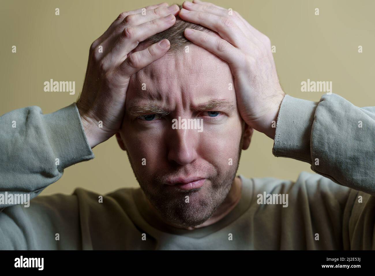 The man put his hands on his head. Portrait of a young man making faces ...