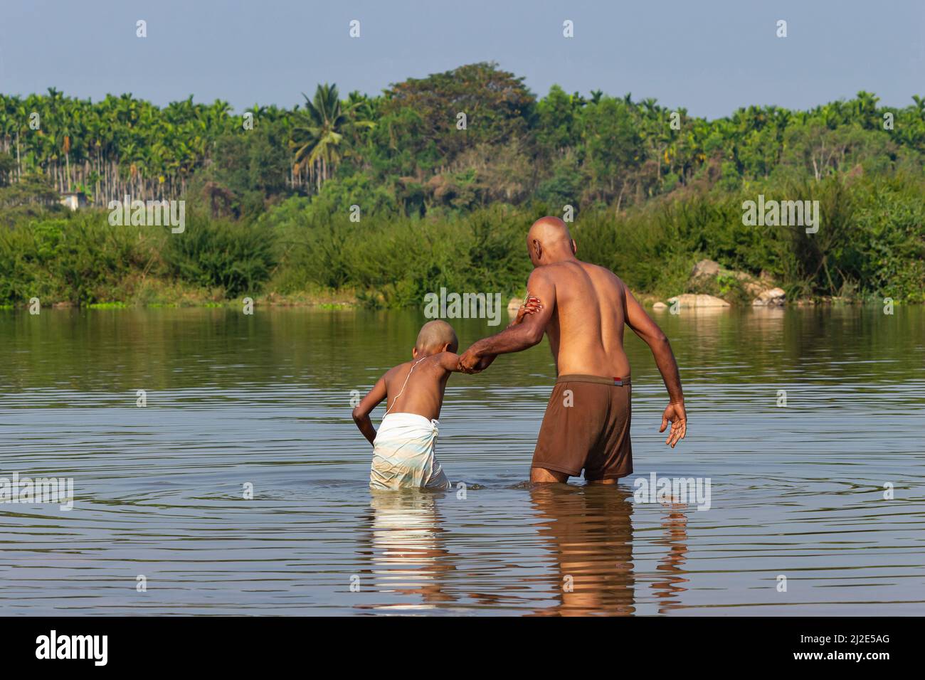 INDIA, KARNATAKA, SHIVAMOGA, February 2022, Man Dipping Boy in River ...