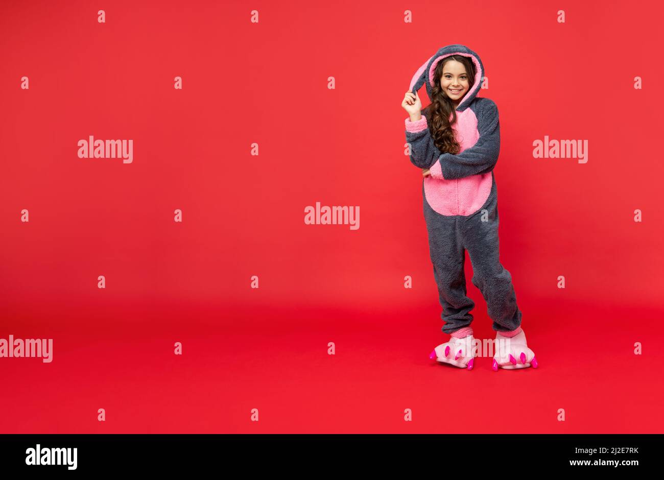 full length of happy child in cozy sleepwear on red background with ...