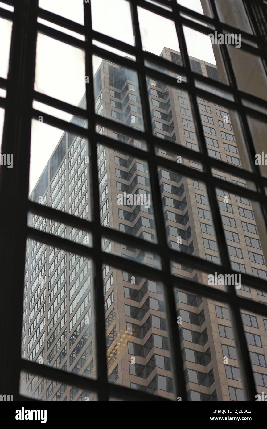 A very tall and huge window with a skyscraper showing thru the glazing ...