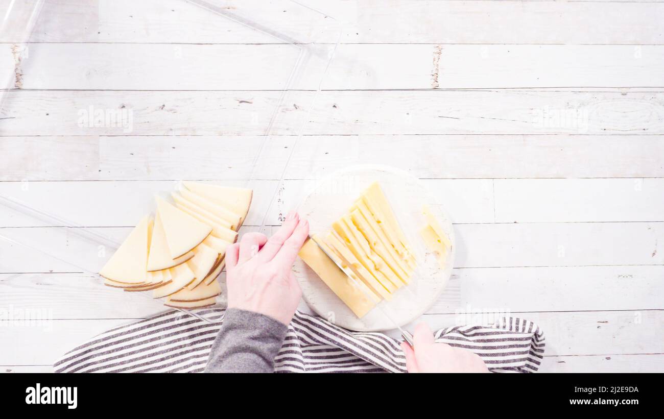 Flat lay. Step by step. Slicing a gourmet cheese on a white cutting ...