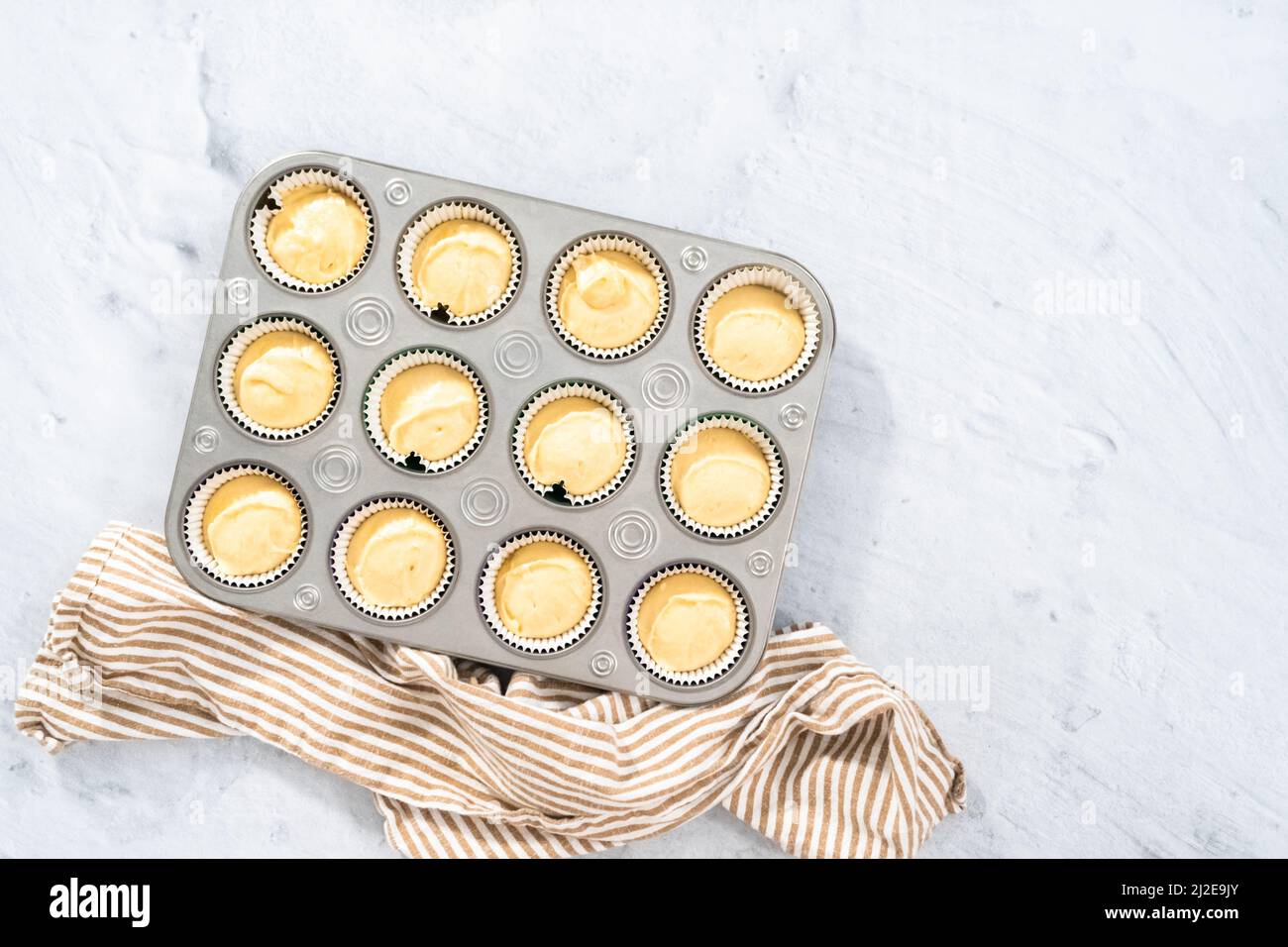 Flat lay. Vanilla cupcake batter in foil cupcake liners to bake Mardi ...