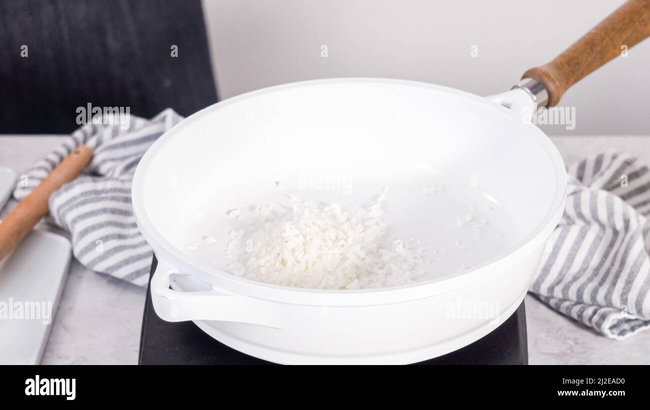 Step by step. Toasting coconut flakes on a nonstick white frying pan ...