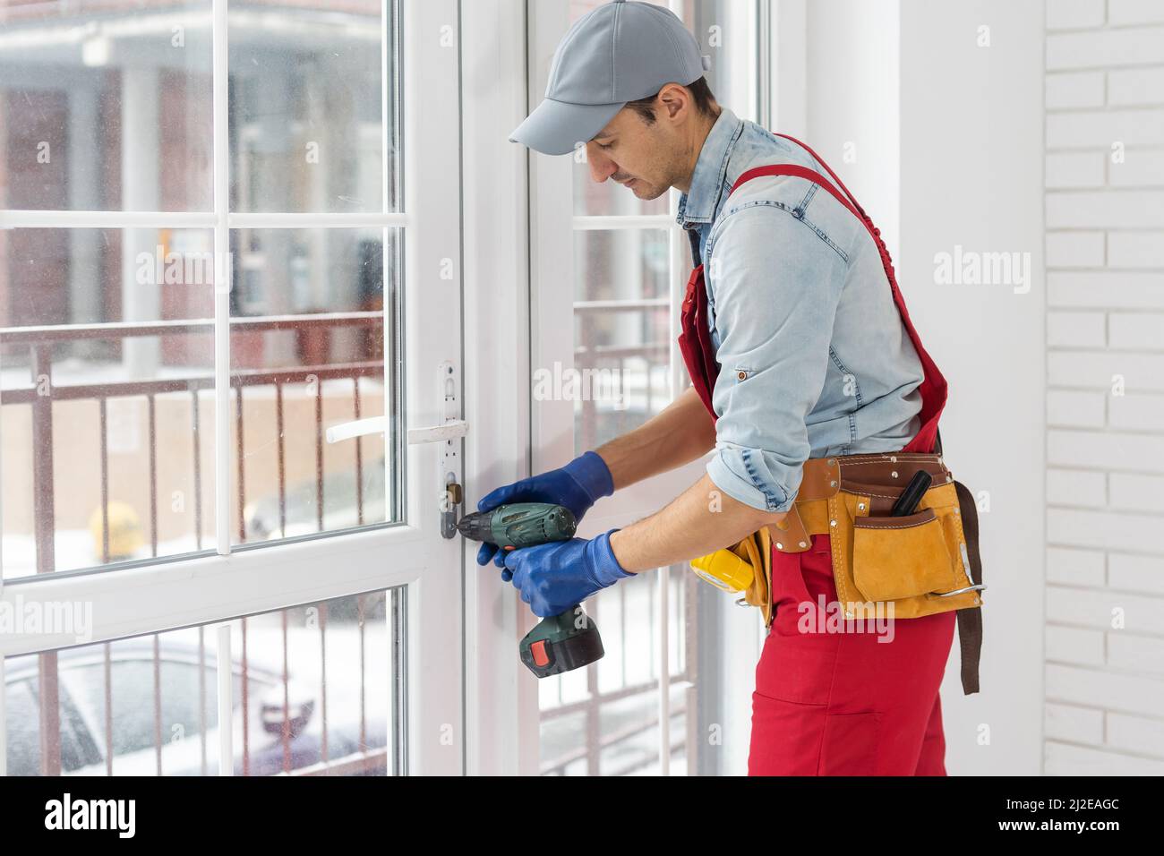 Man fixing lock to window with electric screwdriver Stock Photo - Alamy