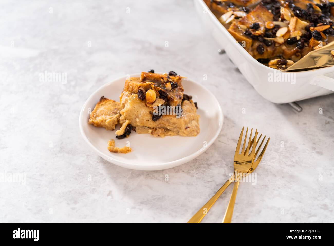 Serving freshly baked bread pudding with raising and almond slivers in ...
