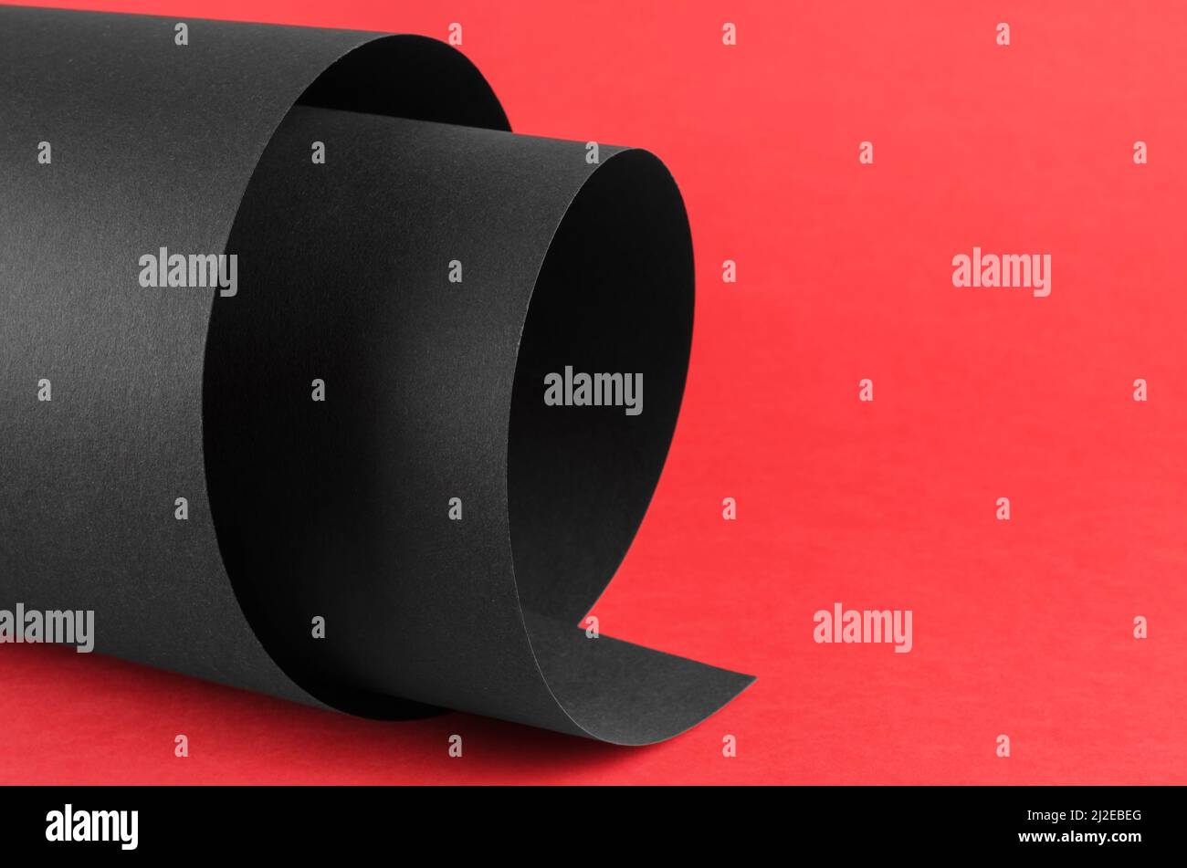 Black rolled sheet of paper on a red background Stock Photo - Alamy